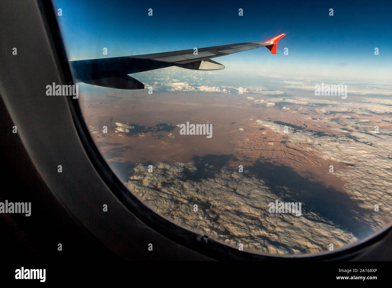 Aircraft wing flying over desert seen through window Stock Photo - Alamy