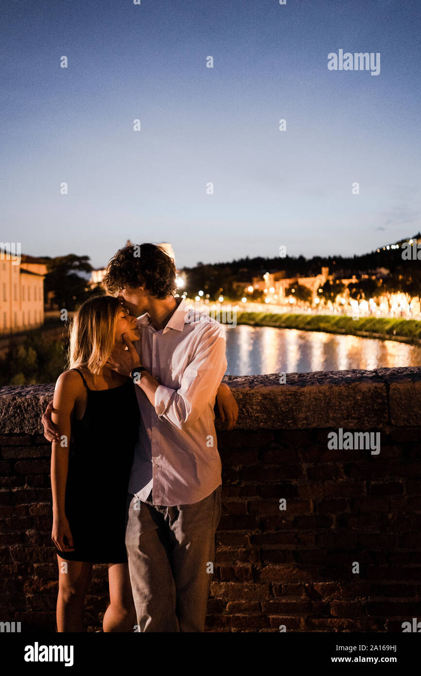 Affectionate young couple kissing on a bridge at night hi-res stock ...