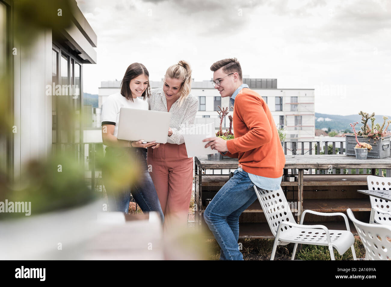 Casual business people with laptop meeting on roof terrace Stock Photo ...