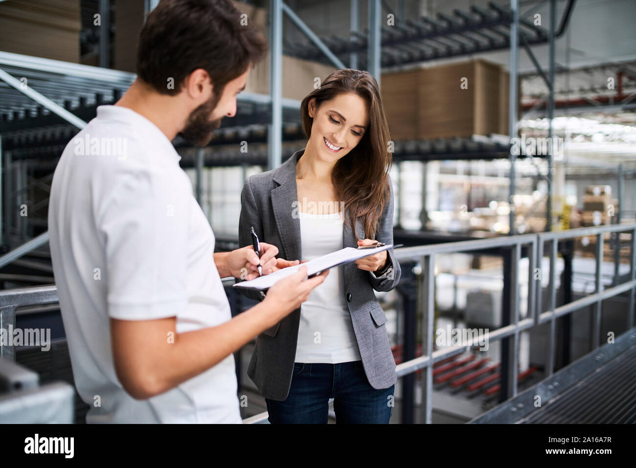 Man signing document in factory held by businesswoman Stock Photo - Alamy