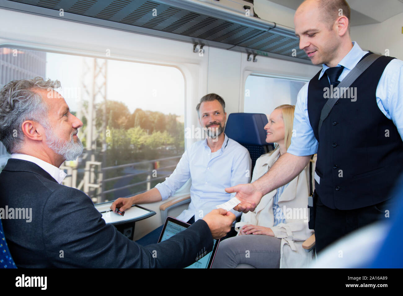 Conductor checking tickets of passengers in a train Stock Photo - Alamy