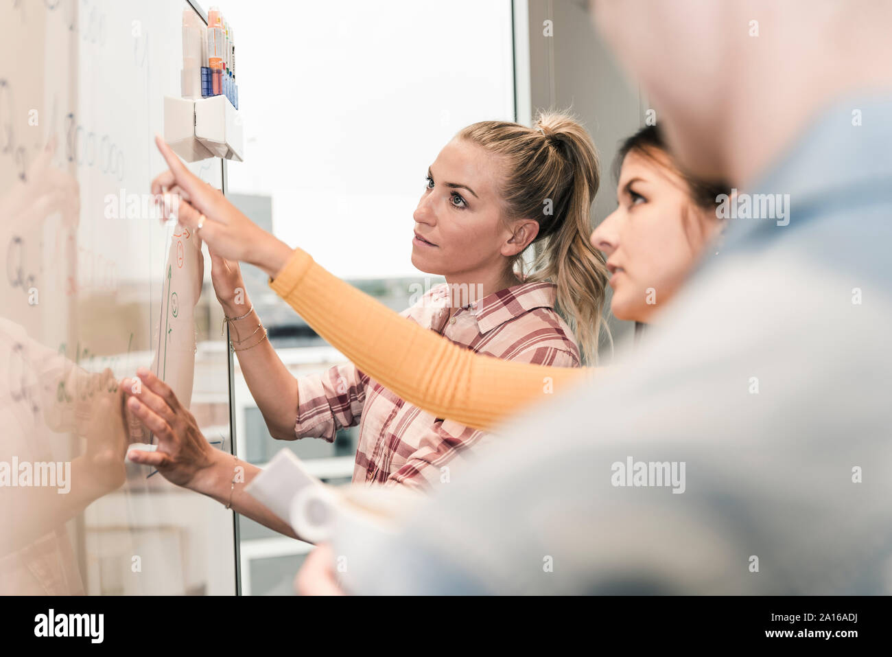 Colleagues working whiteboard office hi-res stock photography and ...