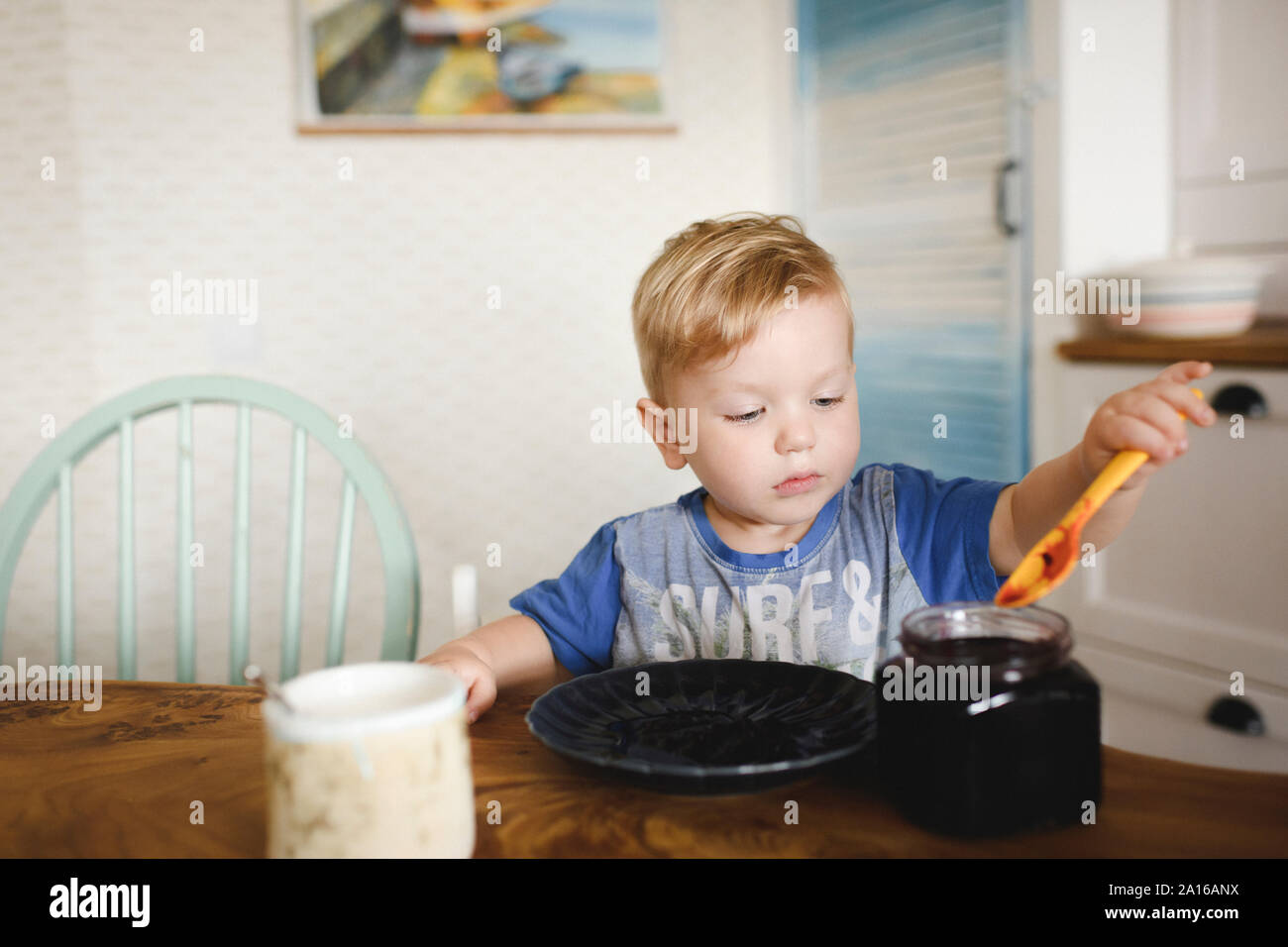 Cute little boy eating blueberry jam Stock Photo - Alamy
