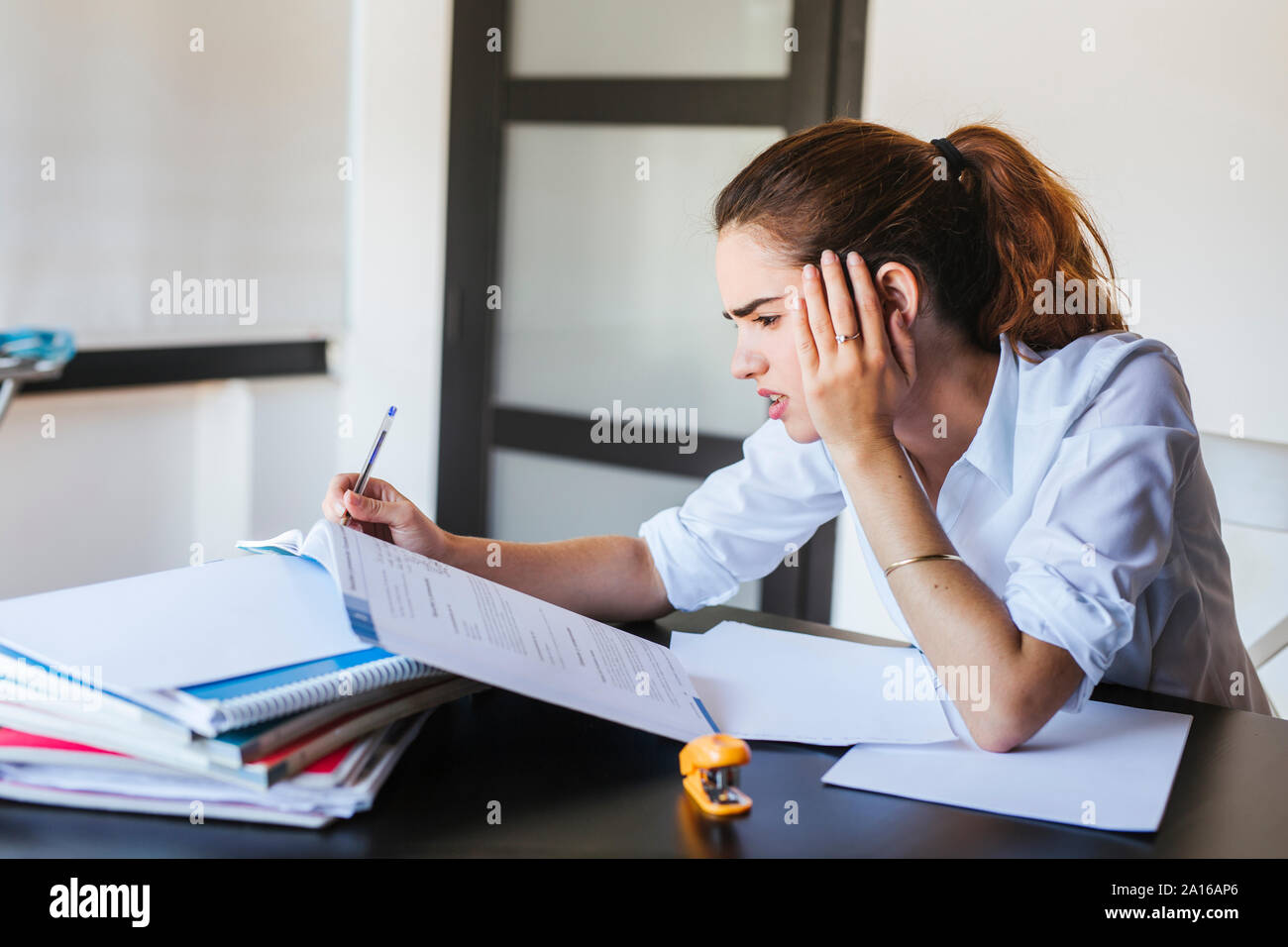 Frustrated female student with documents at desk at home Stock Photo ...