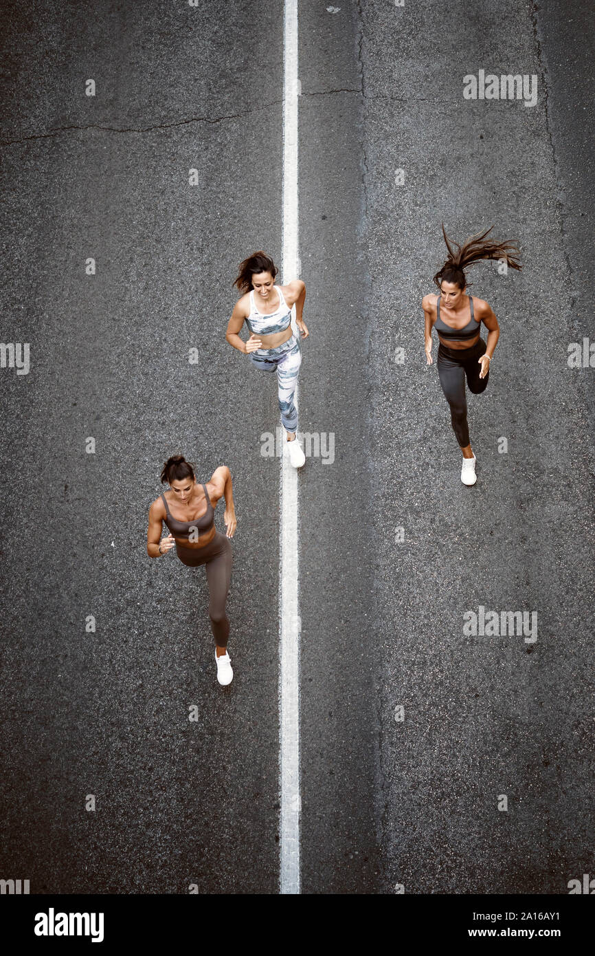 Top view of three sporty young women running on a street Stock Photo ...