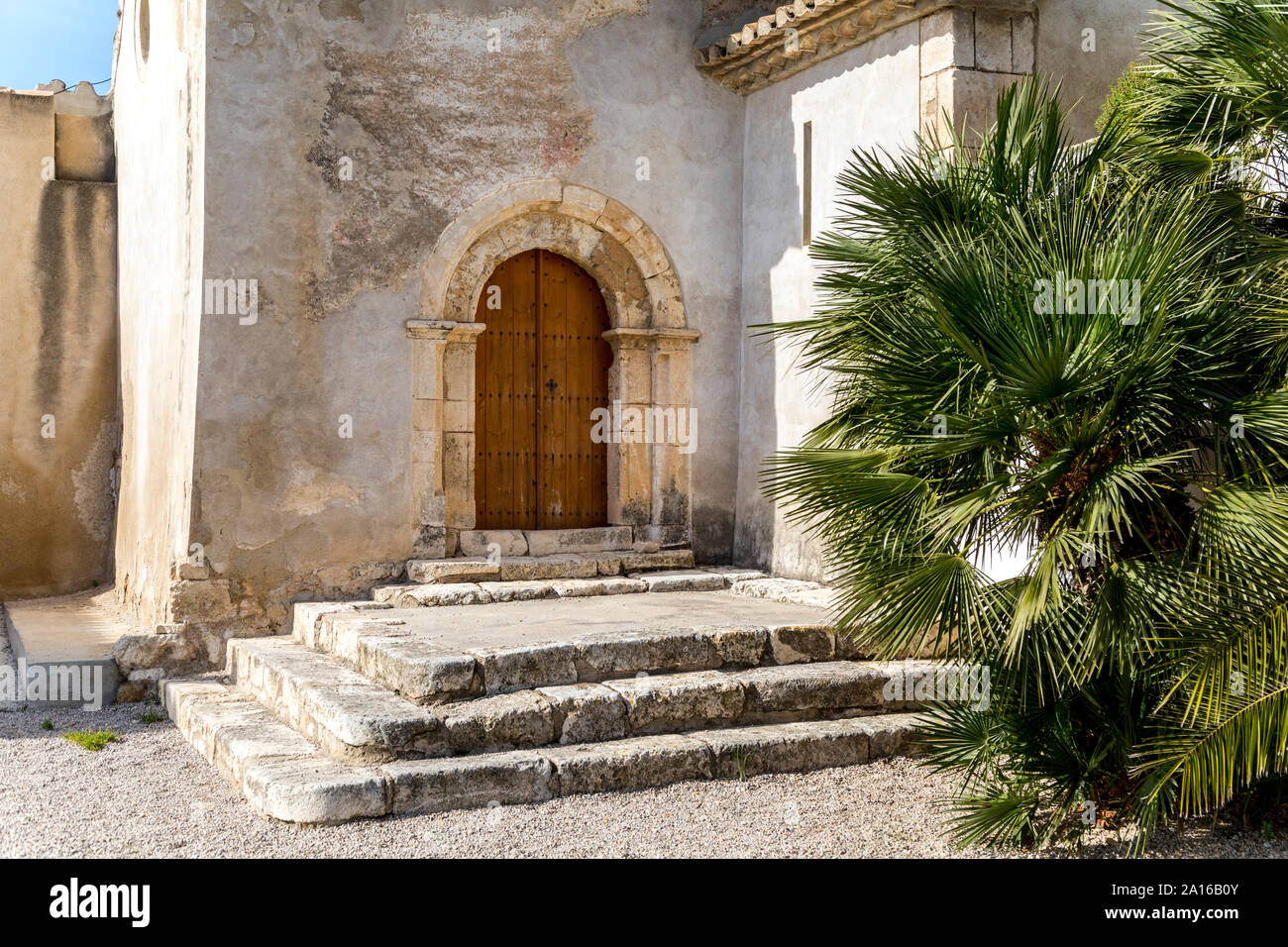 Arched wooden doorway and weathered steps on Spanish building exterior ...