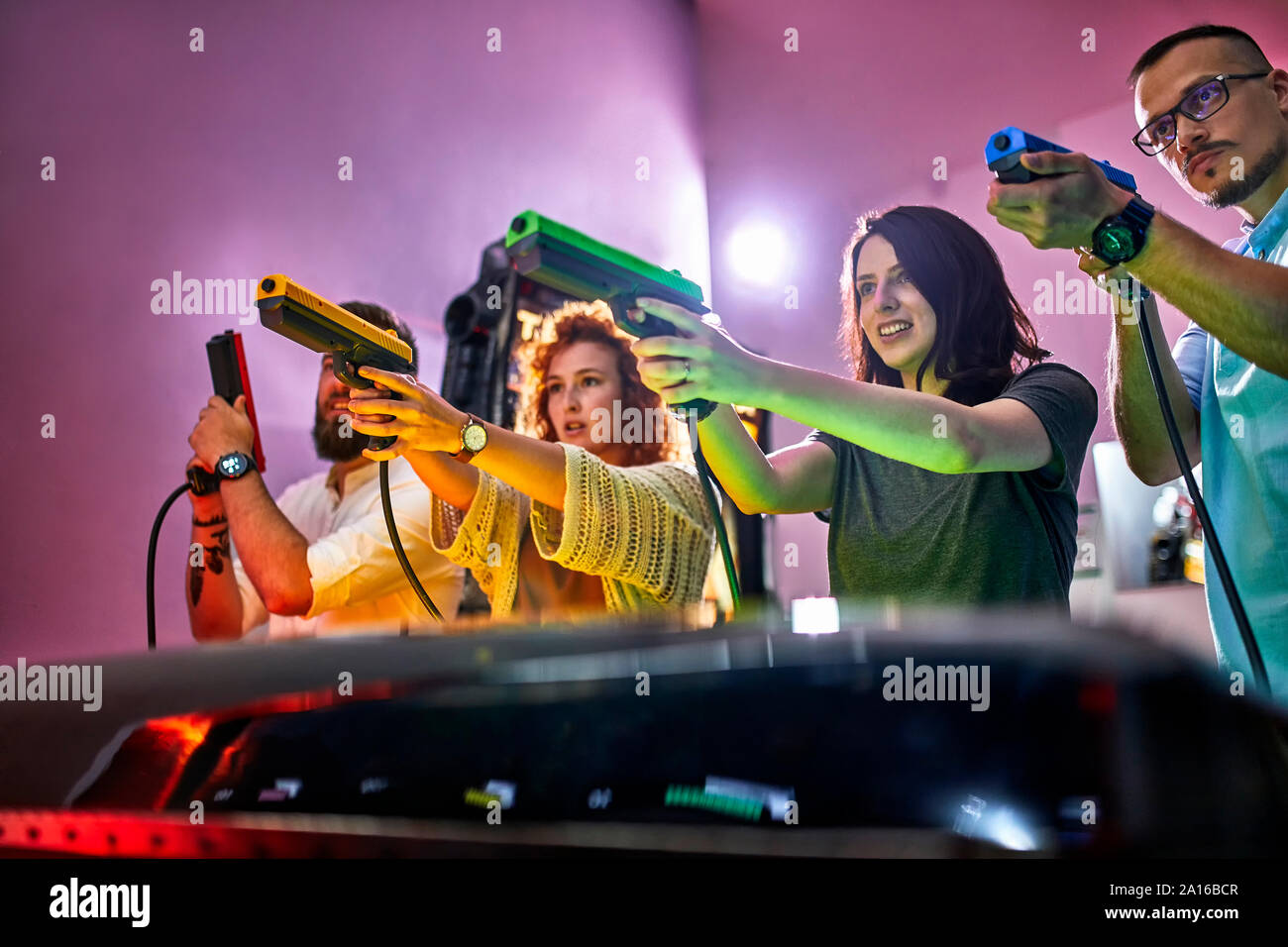Friends playing and shooting with pistols in an amusement arcade Stock ...