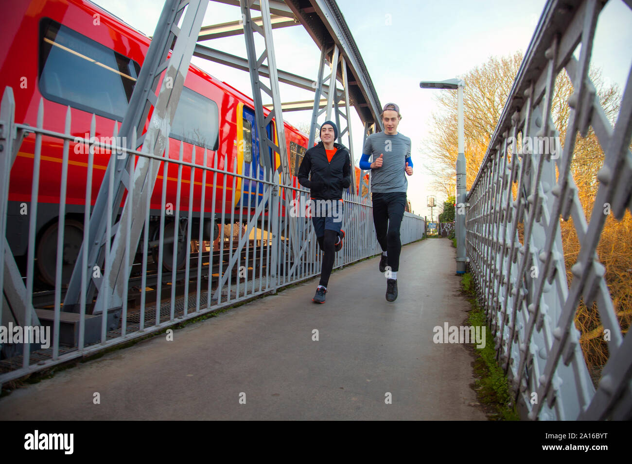 Two teenagers running over railway bridge Stock Photo - Alamy