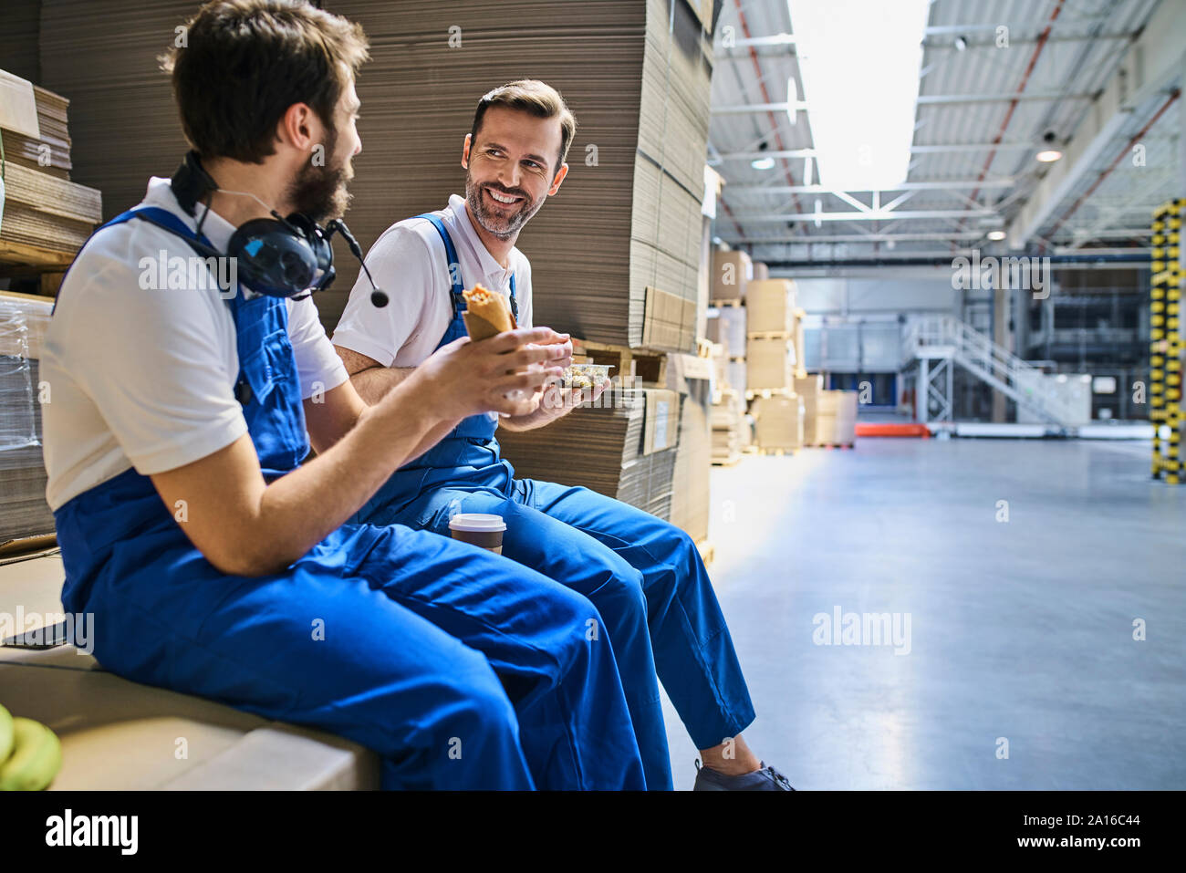 Two happy workers having lunch break in factory Stock Photo - Alamy