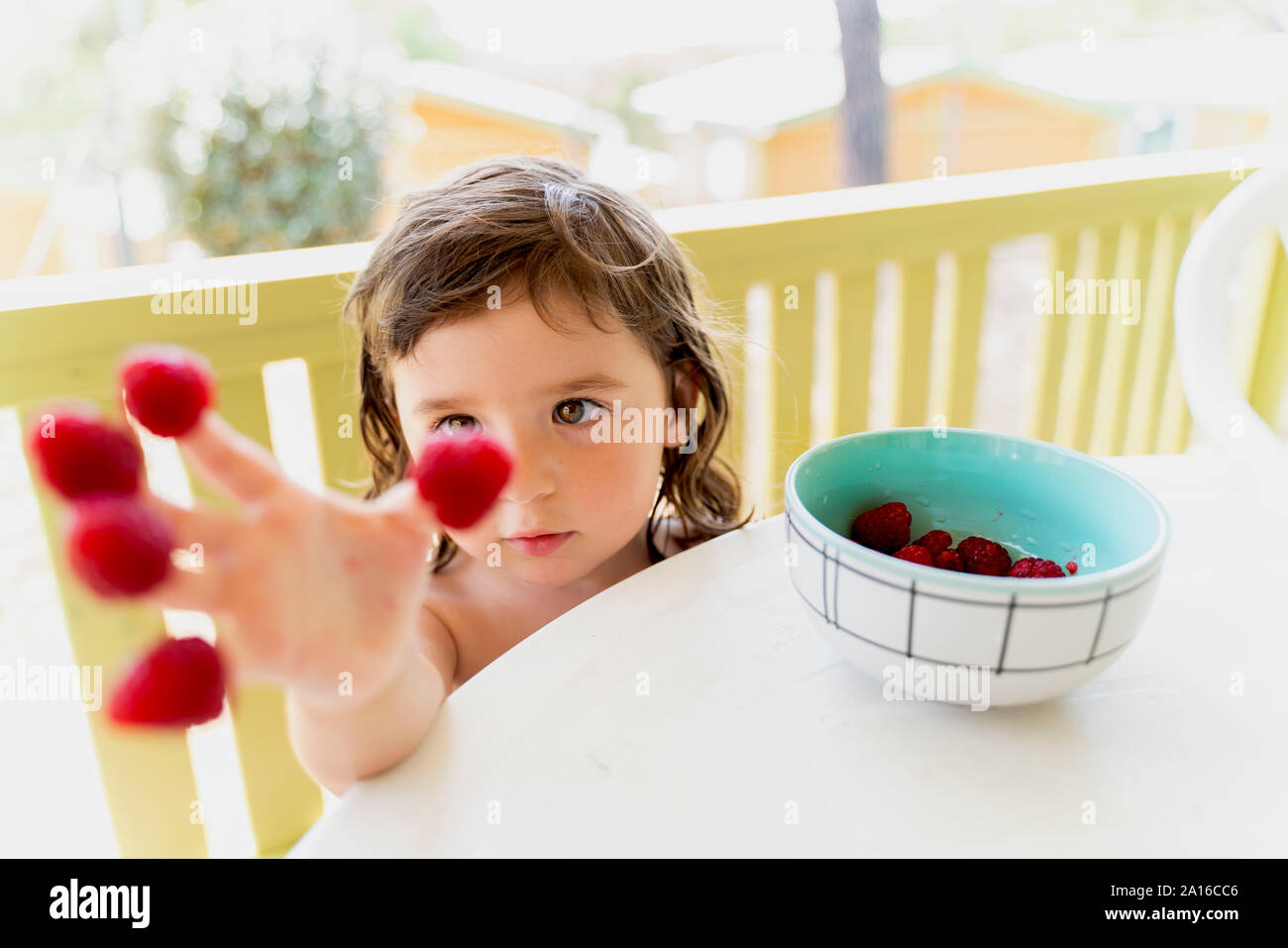 Cute little girl with raspberries on her fingertips Stock Photo - Alamy