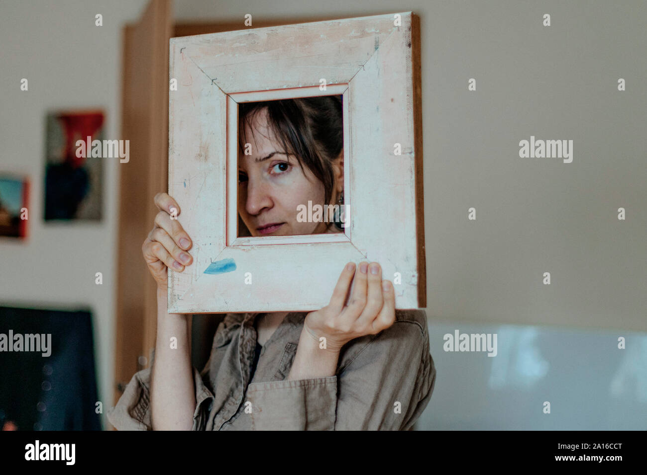 Portrait of a female painter in her studio looking through picture ...