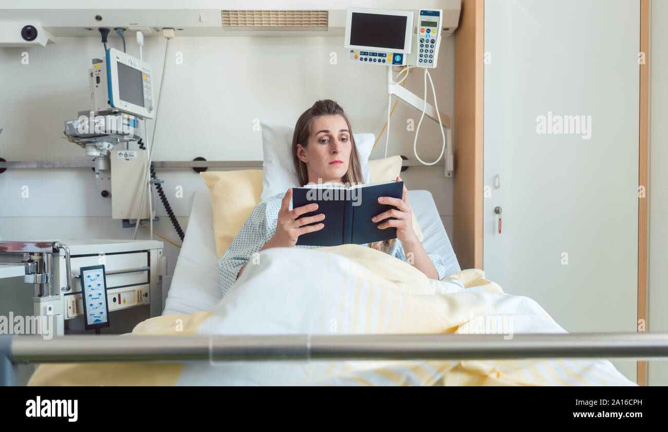 Woman in hospital bed reading the bible to find consolation Stock Photo ...