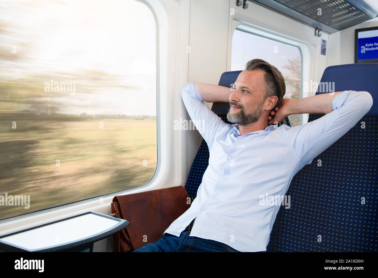 Mature man sitting in a train, relaxing Stock Photo - Alamy