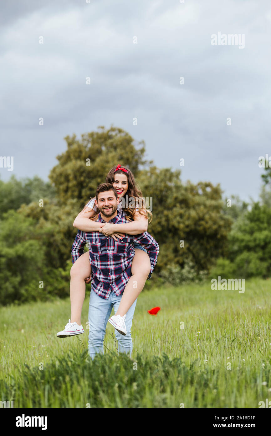 Young man carrying girlfriend piggyback in nature Stock Photo - Alamy