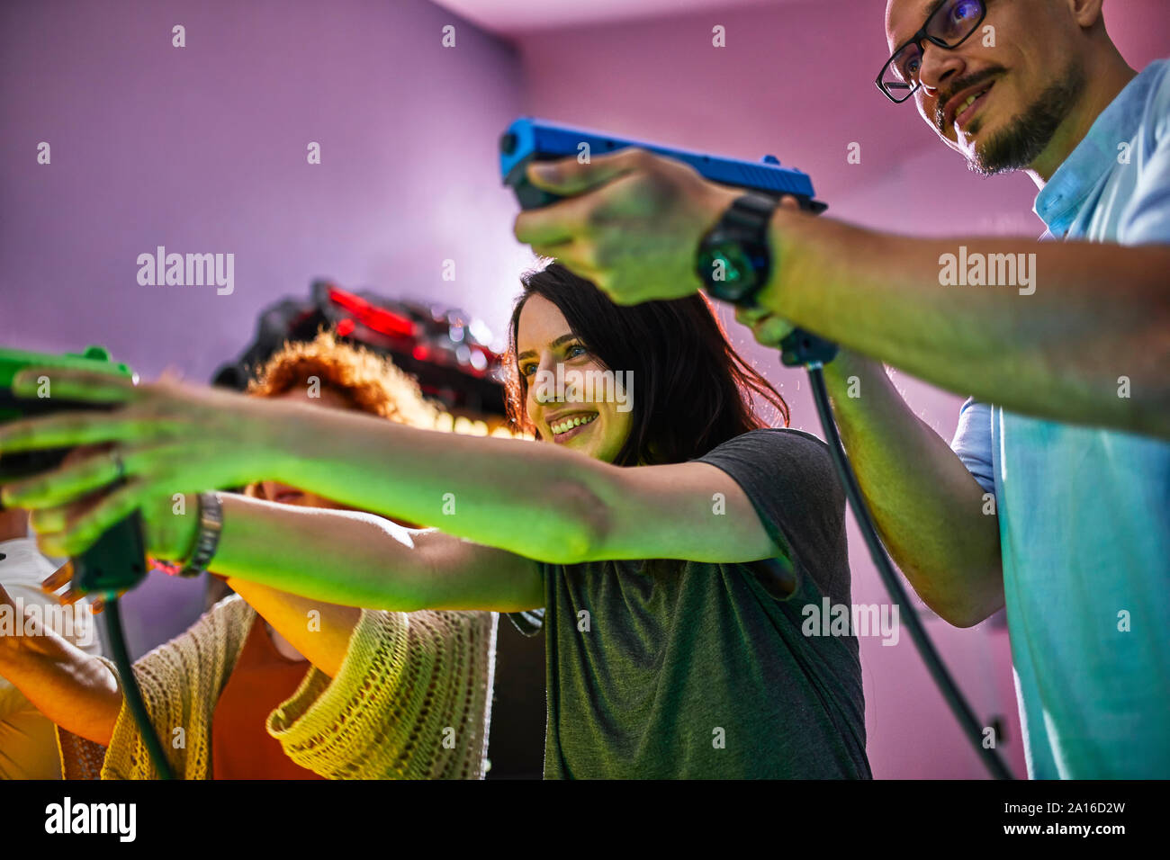 Happy friends playing and shooting with pistols in an amusement arcade ...