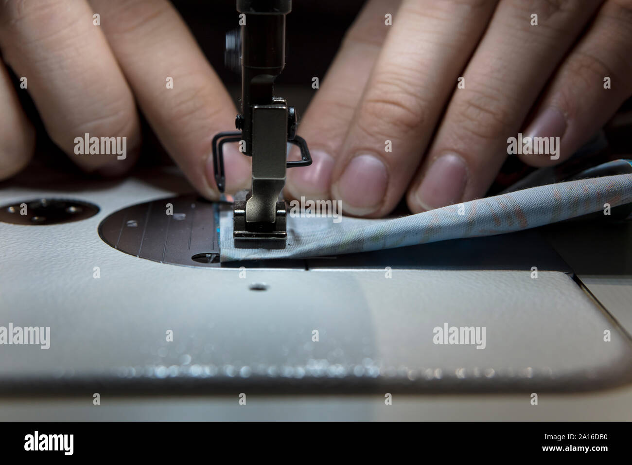 Fingers holding fabric near sewing machine needle Stock Photo - Alamy