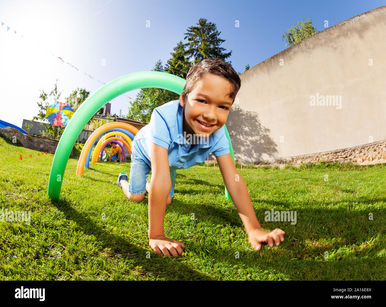 Portrait of a boy pass under obstacle course barriers playing ...