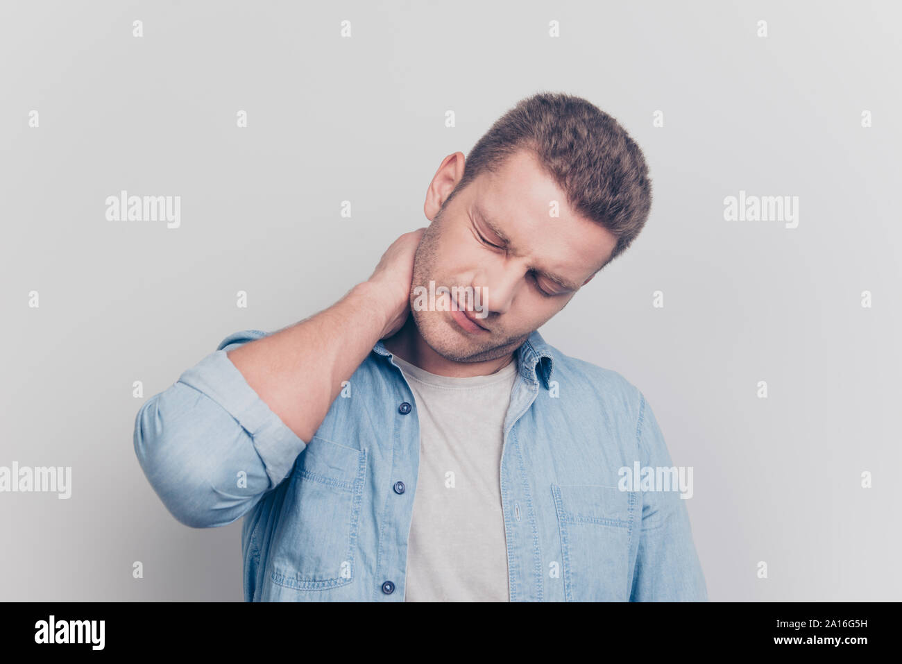 Photo of grumpy face man till head aside hold hands on neck feel Stock ...