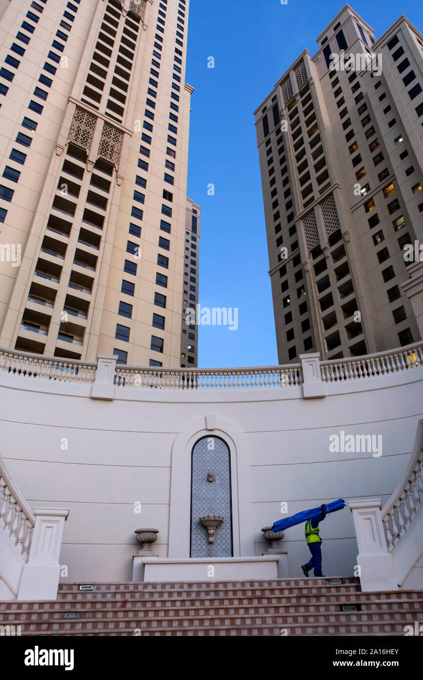 DUBAI - A construction worker carrying building materials amid the ...
