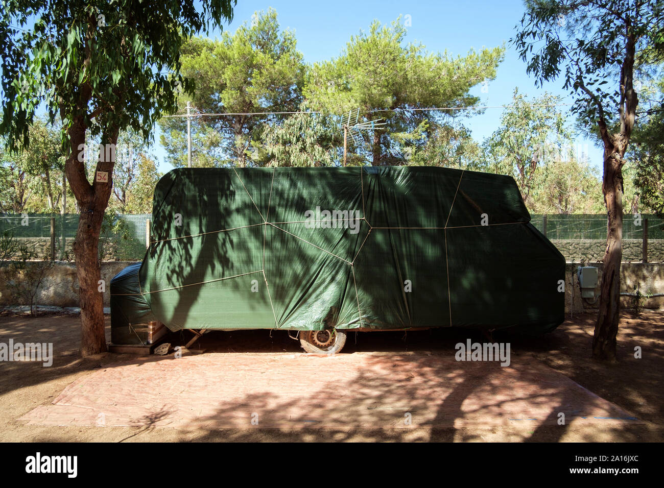 Old caravan trailer packed with tarp in a camp site Stock Photo - Alamy