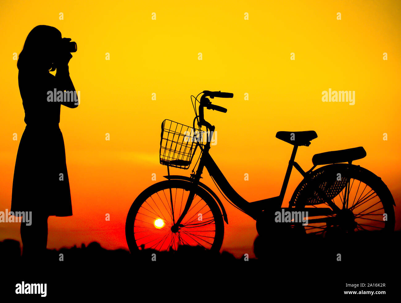 a girl capture the photo with the camera, cycle and background sunset ...