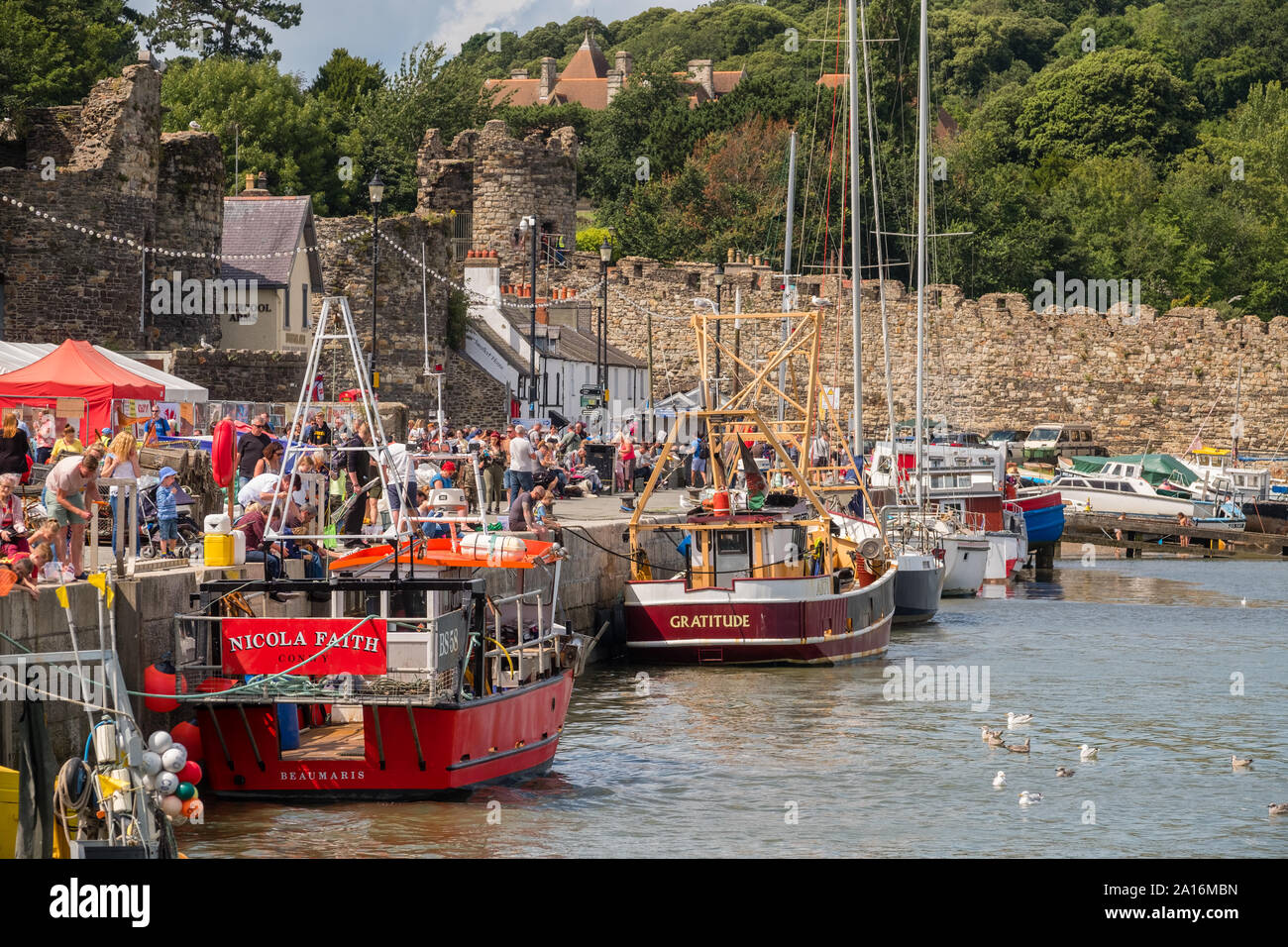 Tourists enjoying a warm and sunny summer afternoon on the quayside in ...