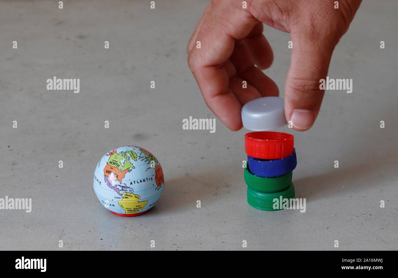 Small earth globe next to hand stacking pet bottle caps representing ...