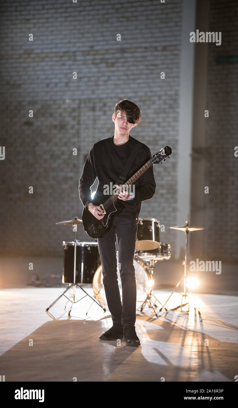 A musician man playing bass guitar in the hangar. Mid shot Stock Photo ...
