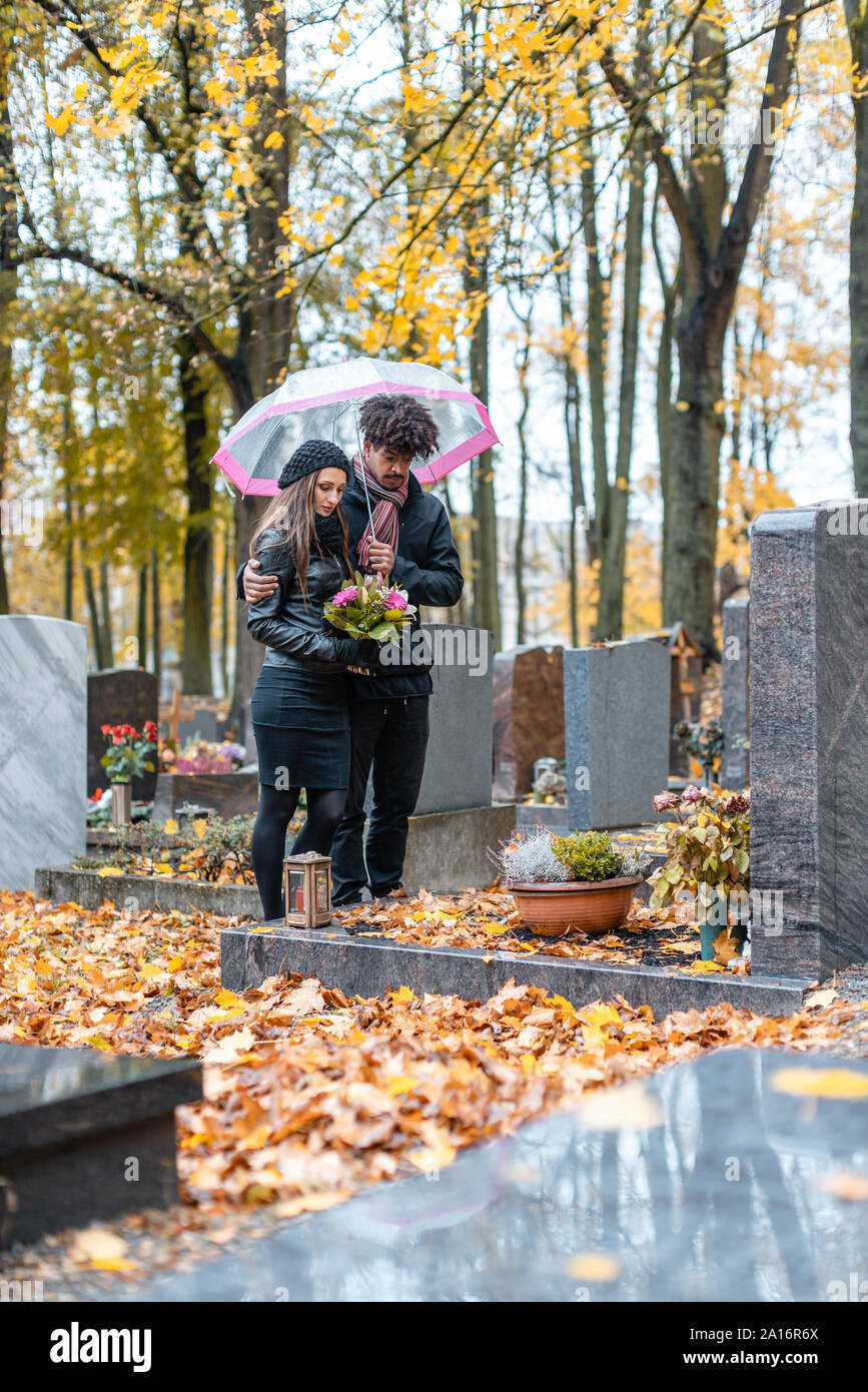 Couple mourning a deceased loved one on cemetery in fall Stock Photo ...