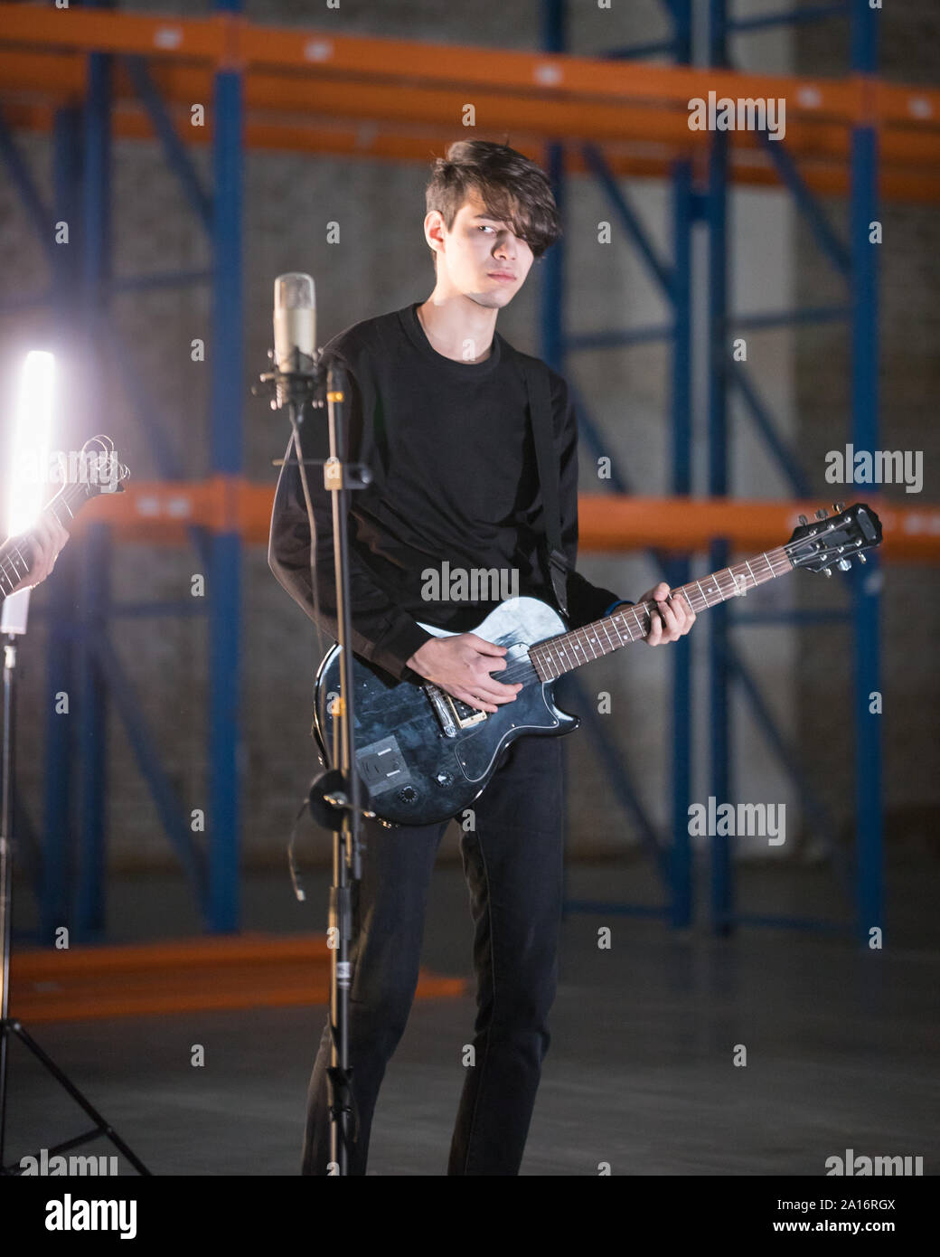 A musician man playing bass guitar in the hangar while rock-group ...