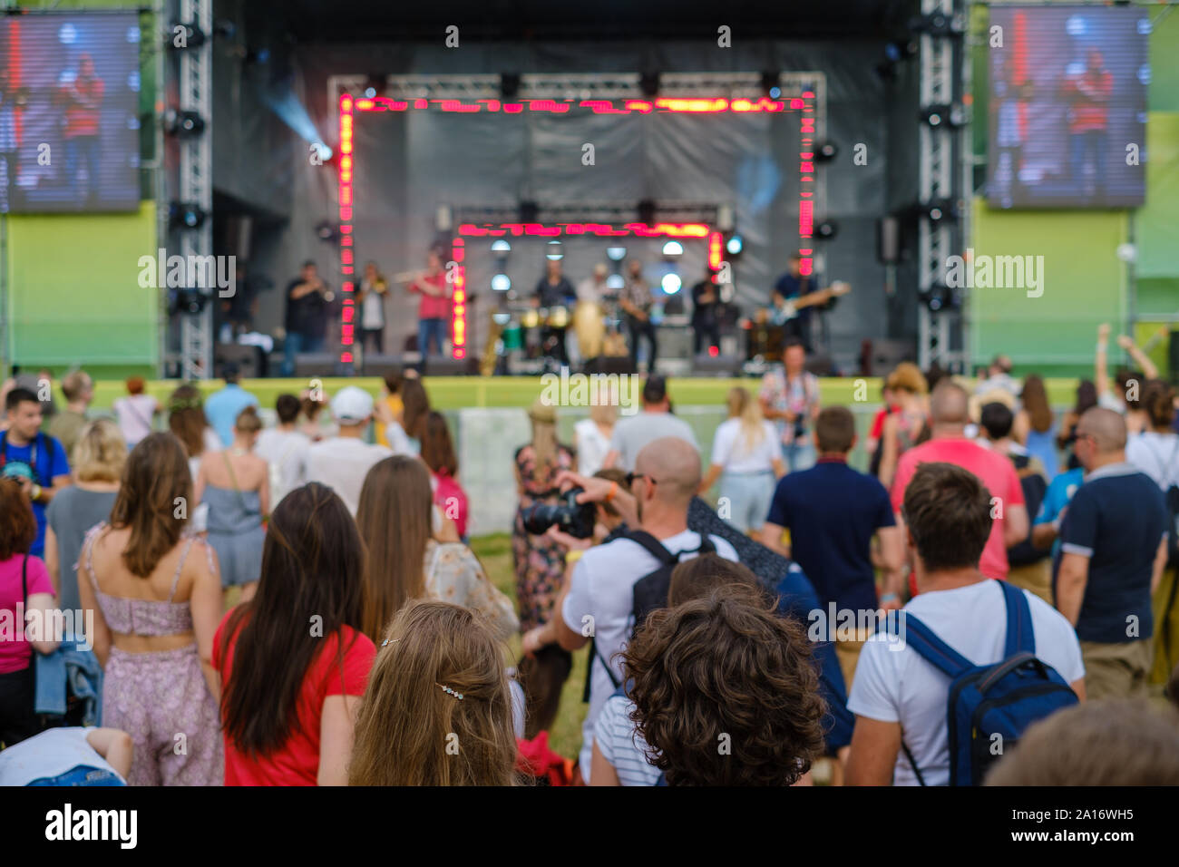 Audience watching concert at open air music festival, rear view, stage ...
