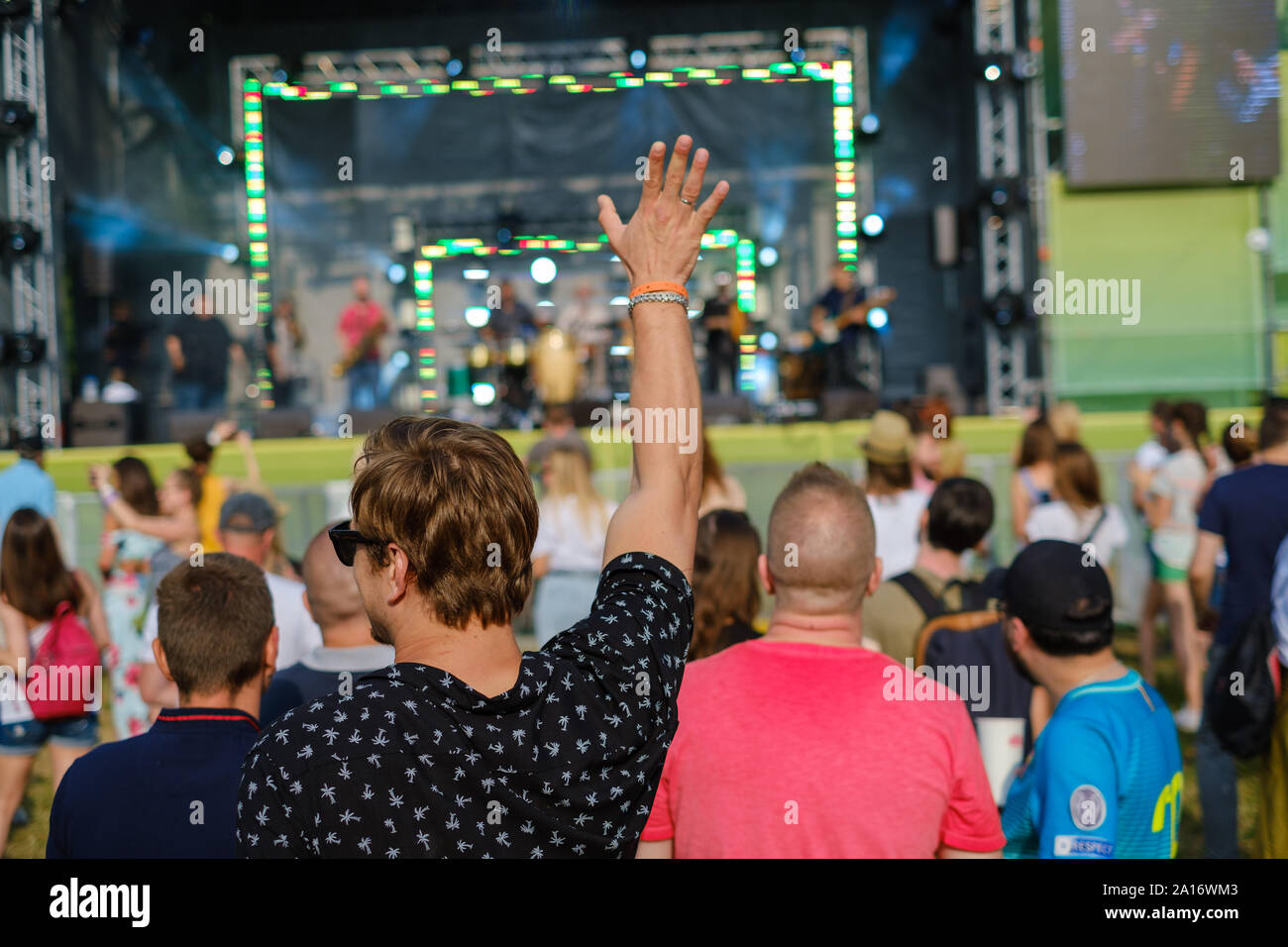 Audience watching concert at open air music festival, rear view, stage ...