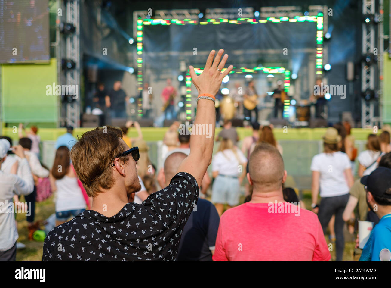 Audience watching concert at open air music festival, rear view, stage ...