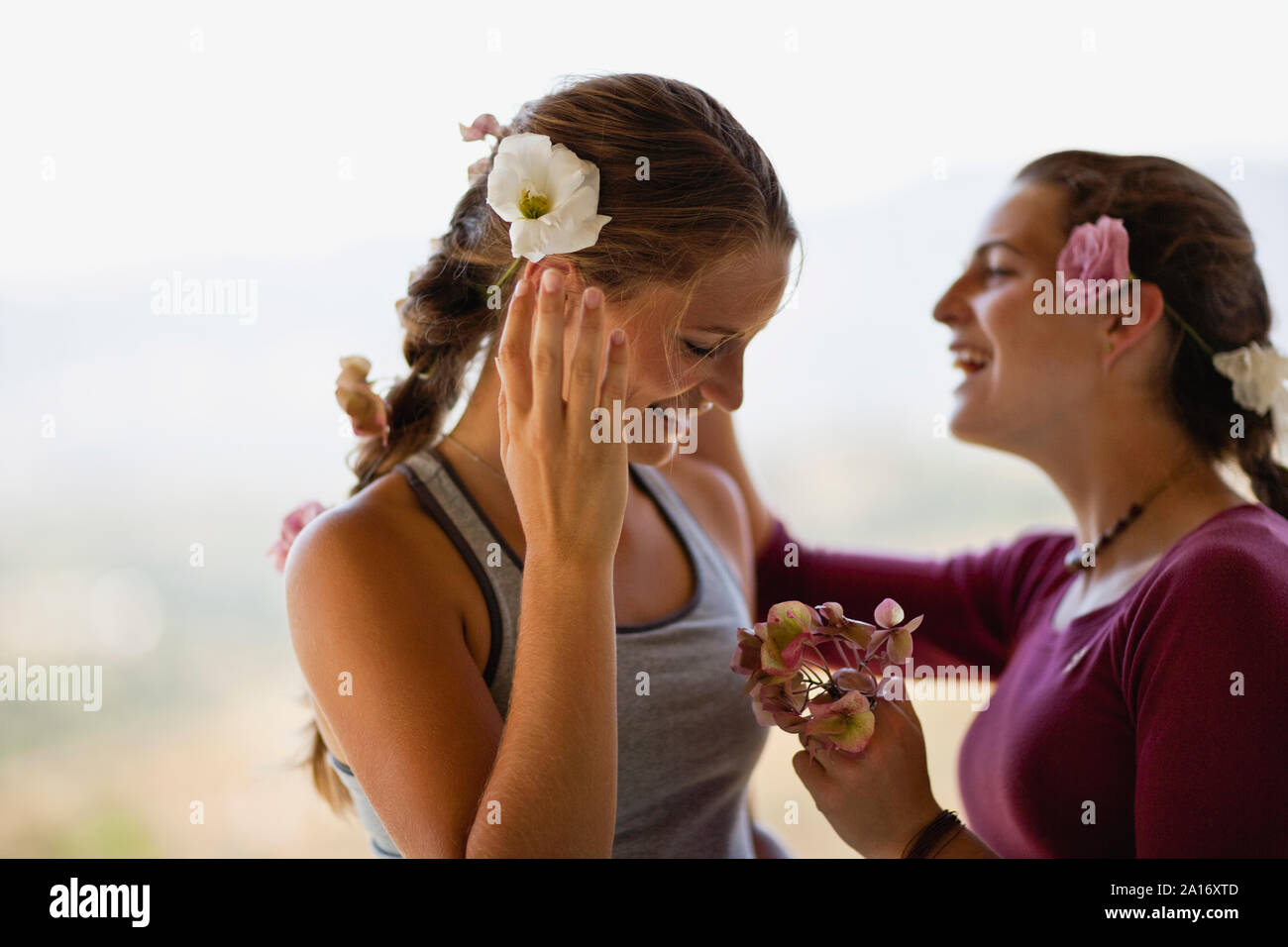 Teenage girls dressing each other's hair with flowers Stock Photo - Alamy