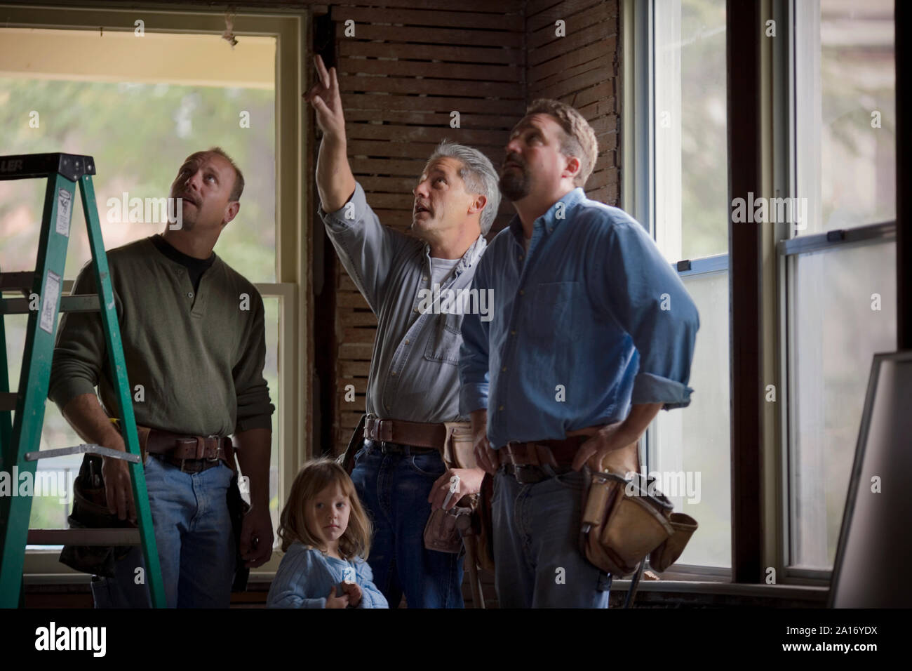 Three male builders standing with a young child inside a room they are ...