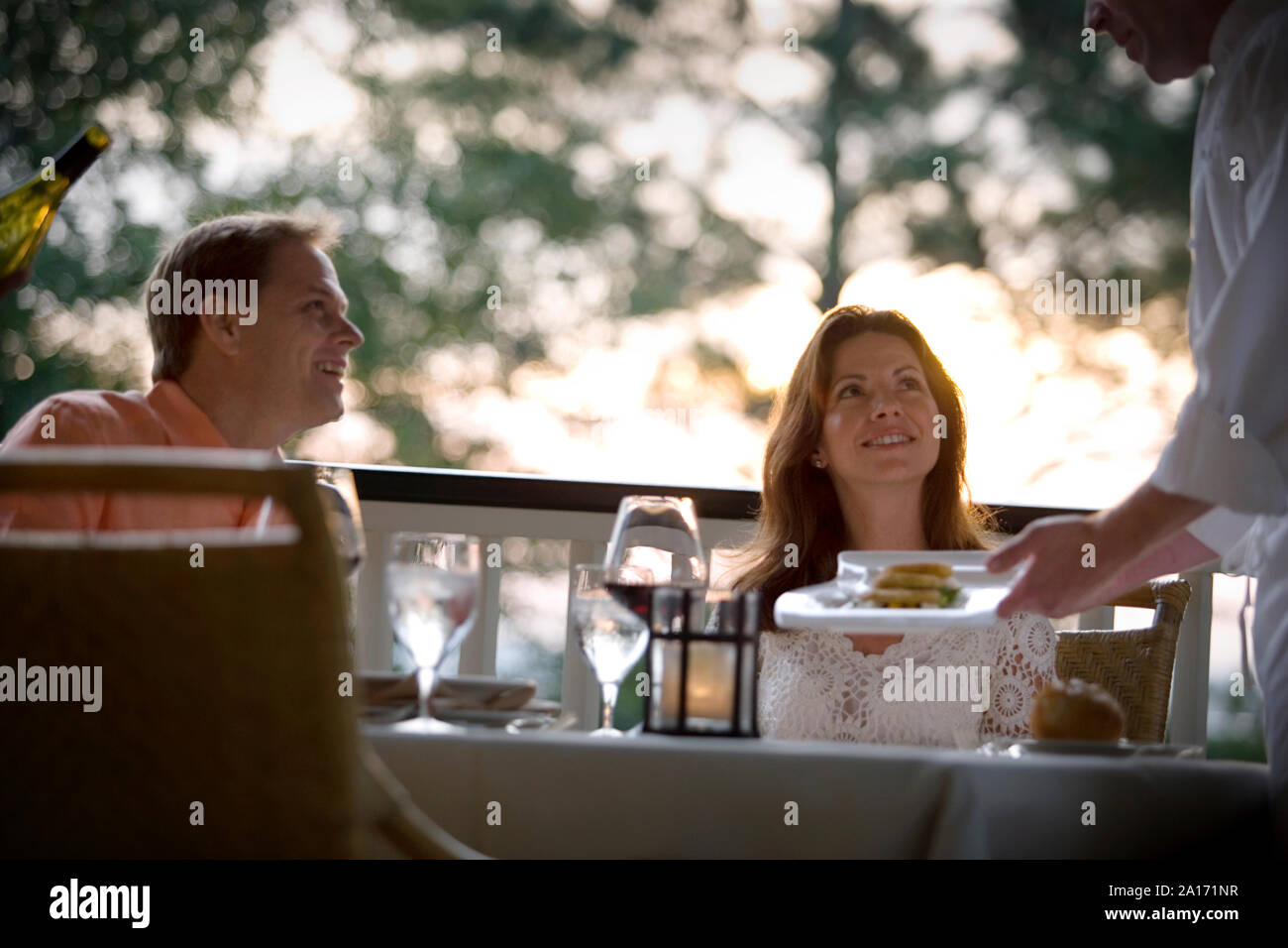 Happy mid-adult couple being served by a waiter at an outdoor ...