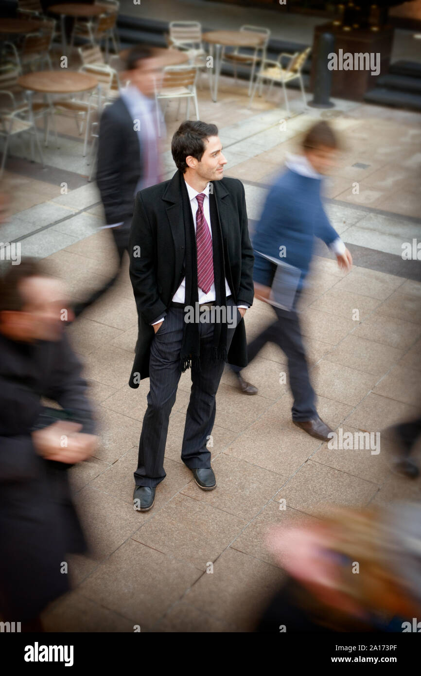 People walking past a young businessman Stock Photo - Alamy