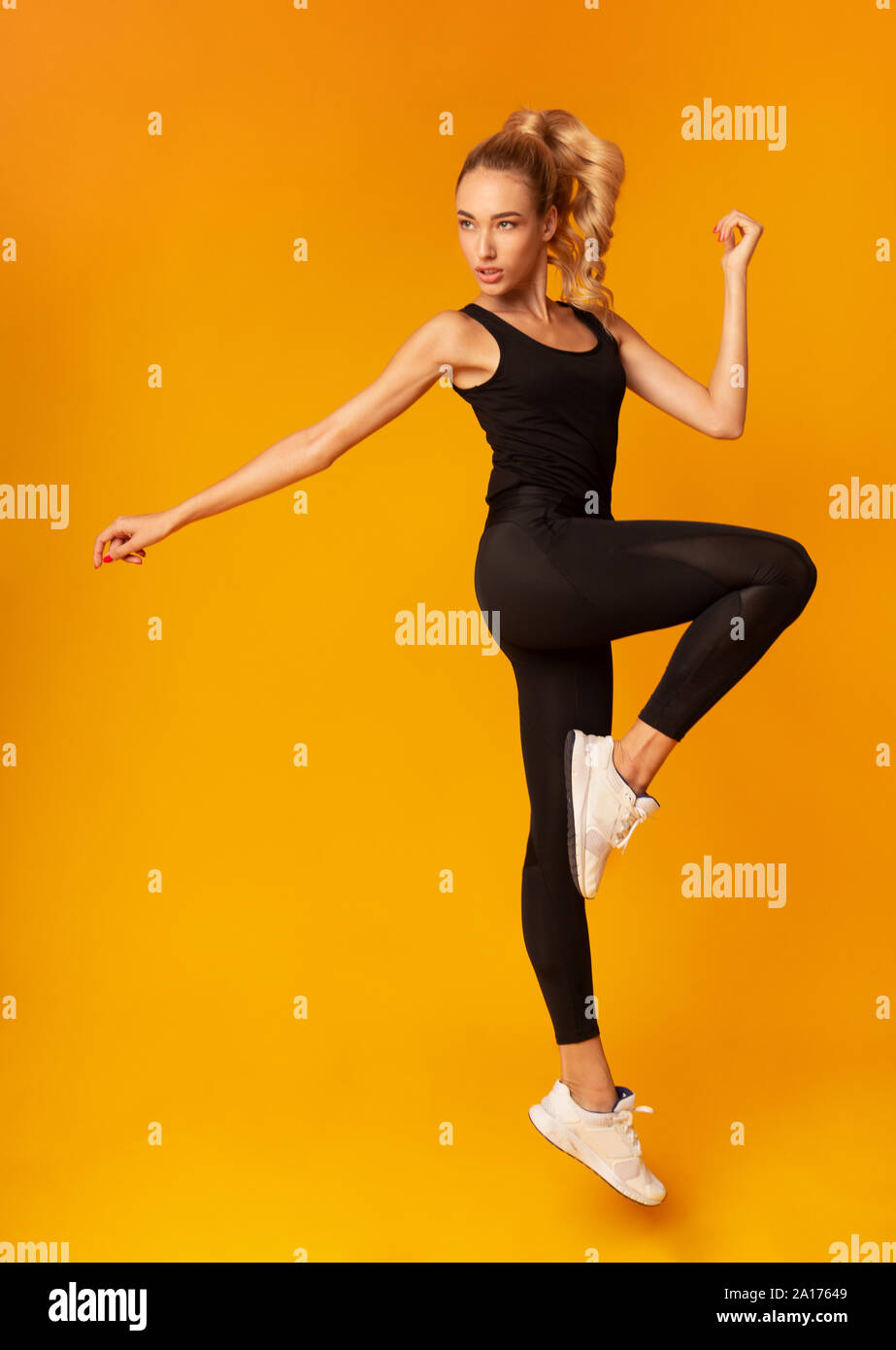 Fit Woman Exercising Jumping In Studio Over Yellow Stock Photo - Alamy