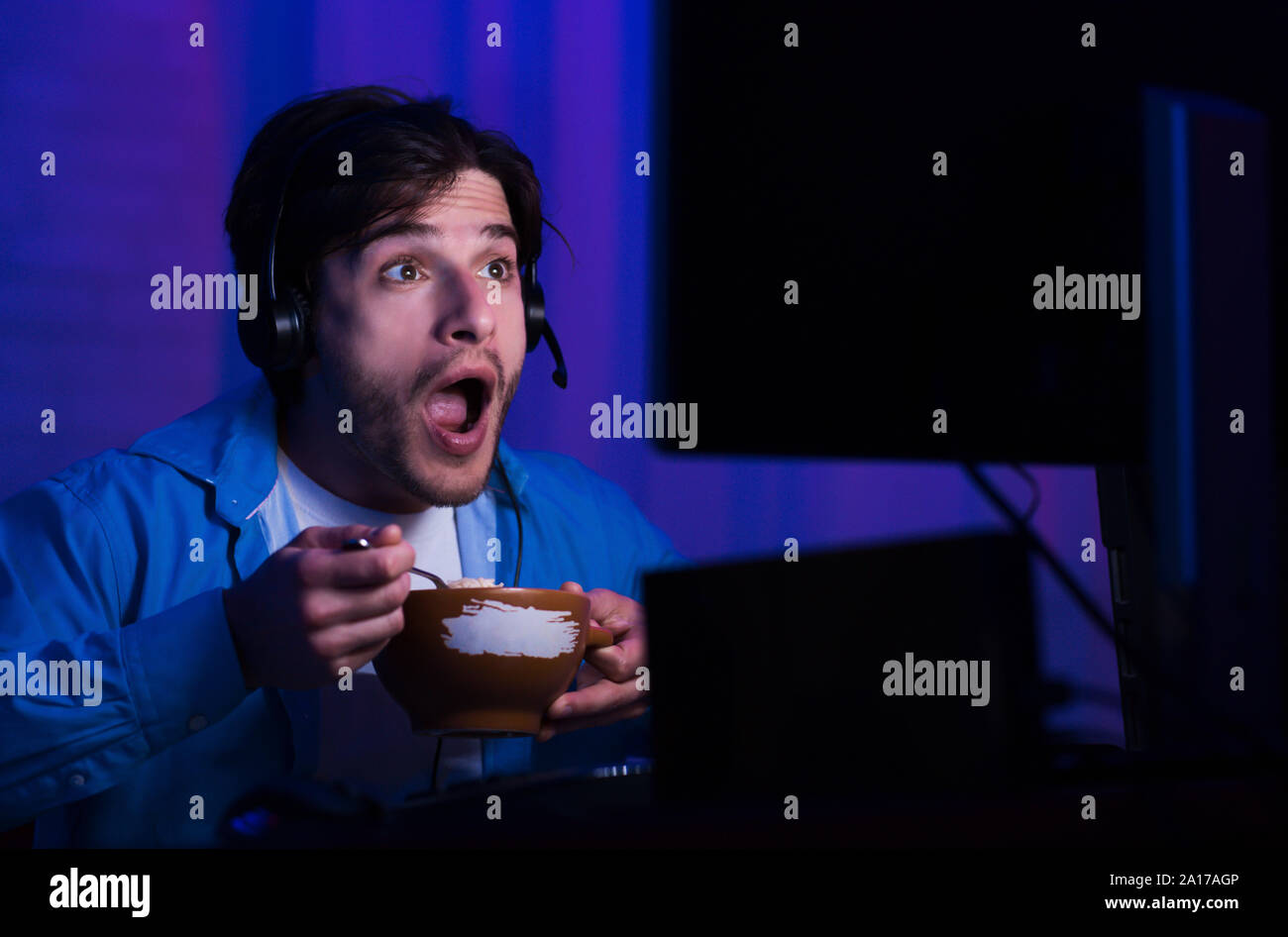 Shocked man eating and playing online games at home Stock Photo - Alamy