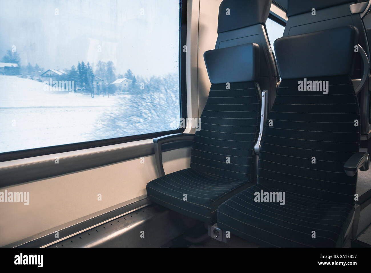 German train interior with black seats and a winter landscape on the ...