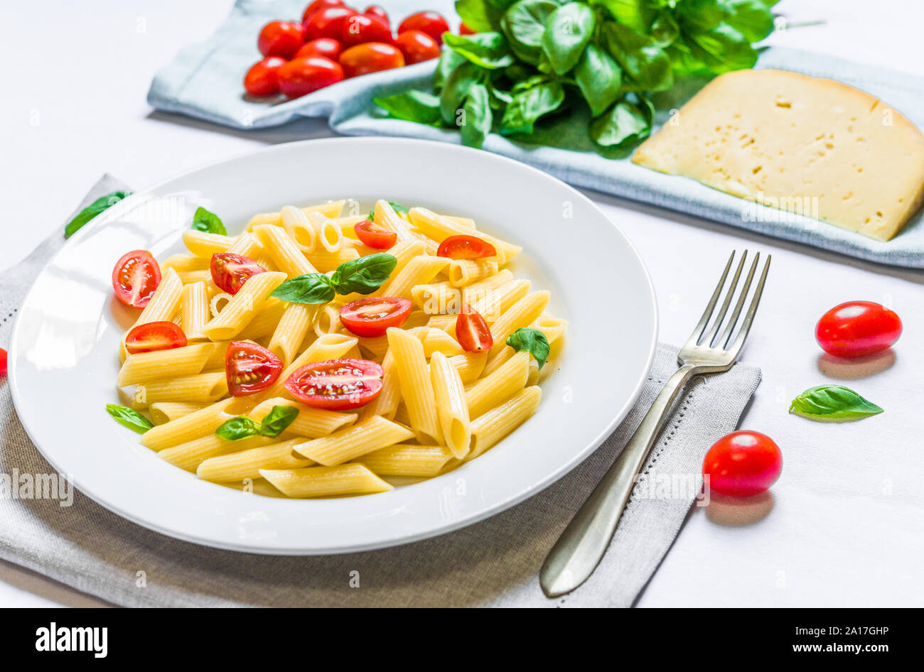 Colorful penne rigate pasta dish with cherry tomatoes and basil leaves ...