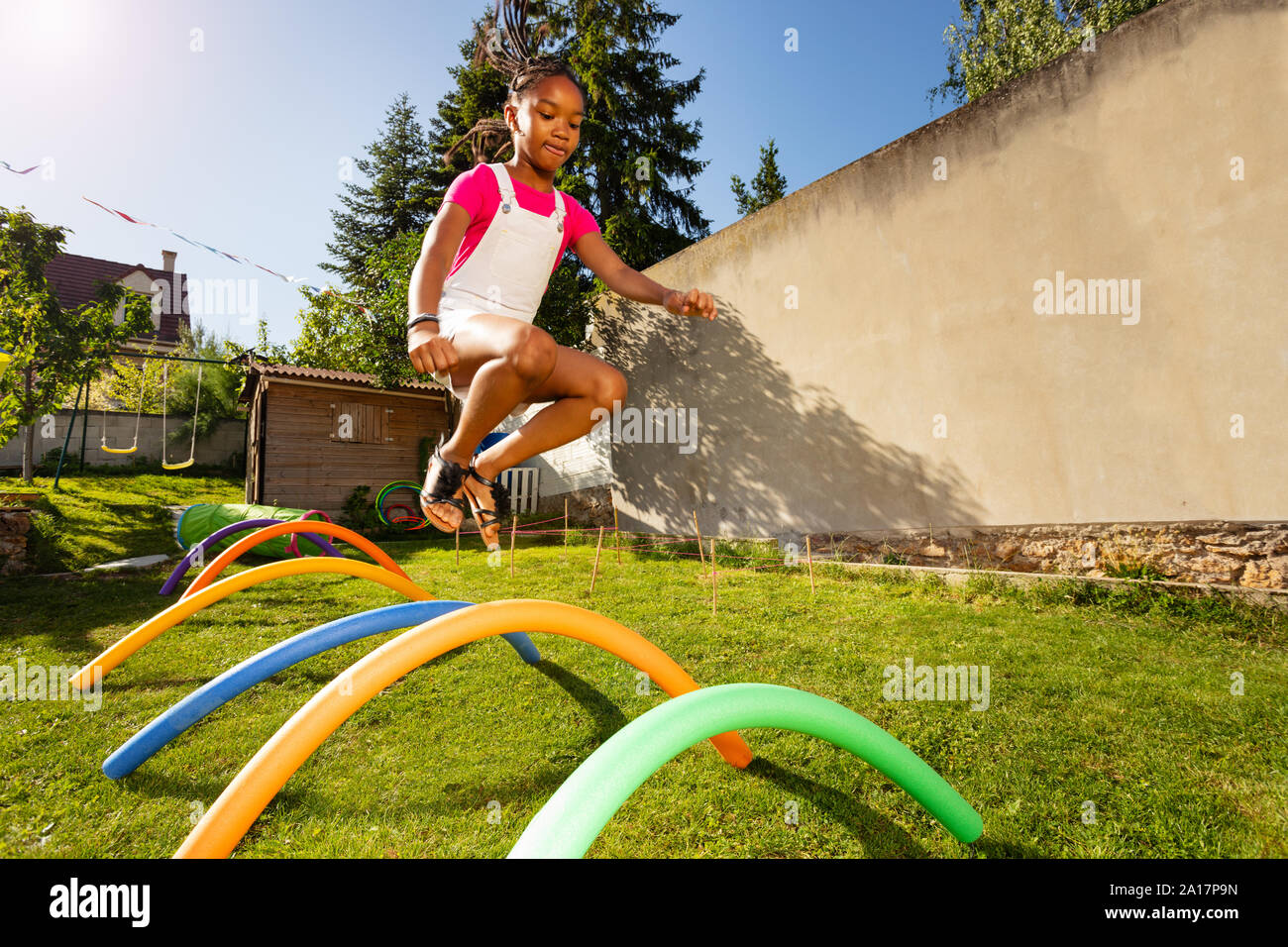 Happy beautiful black girl jump over line of obstacles on the lawn Stock Photo - Alamy