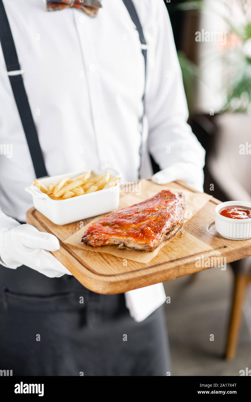 The waiter is holding a wooden plate Delicious Pork ribs. Full rack of ...