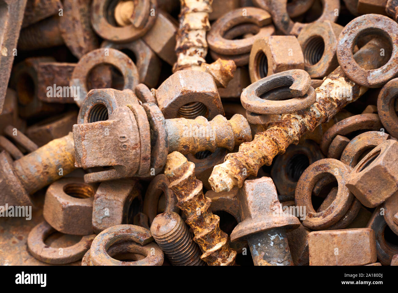 A pile of old and rusty screws, bolts, studs and nuts close to ...
