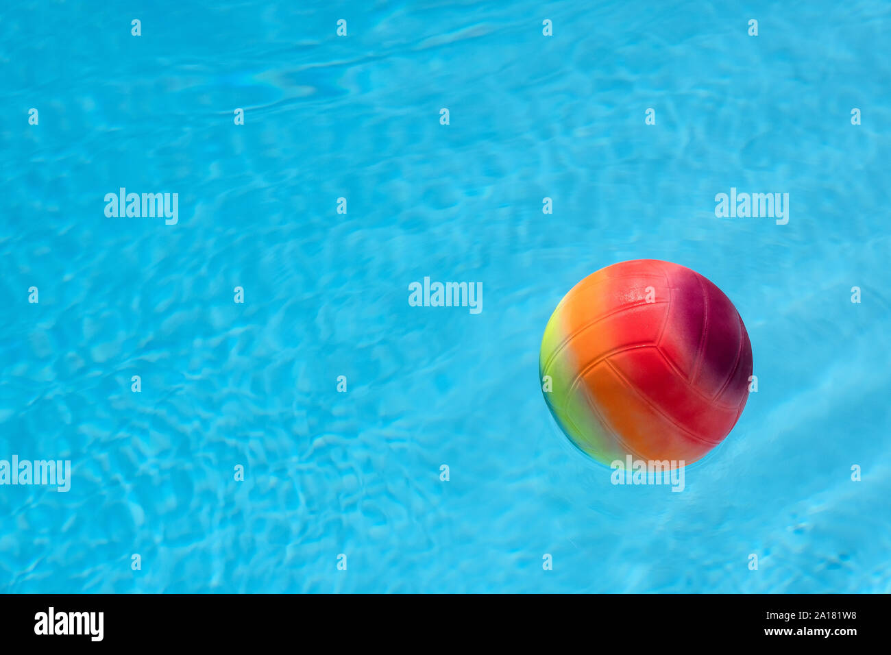 Multi-coloured ball floating on a swimming pool surface Stock Photo - Alamy