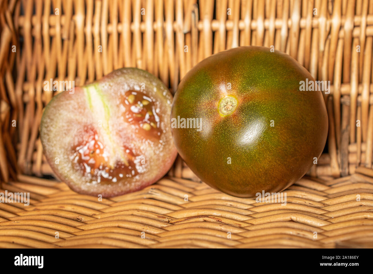 Group of one whole one half of fresh green red tomato with braided rattan behind Stock Photo - Alamy