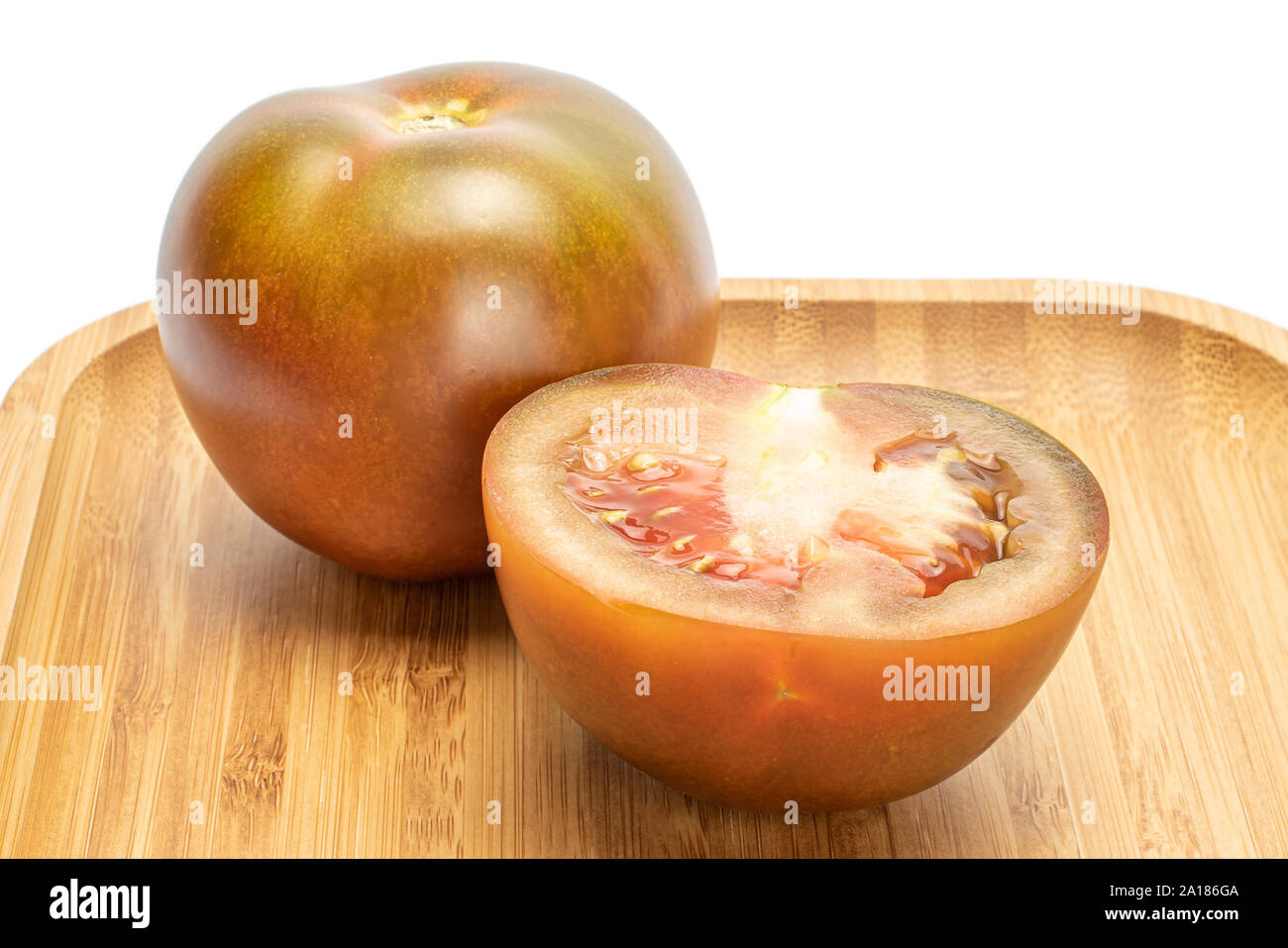 Group of one whole one half of fresh green red tomato on wooden square plate isolated on white ...