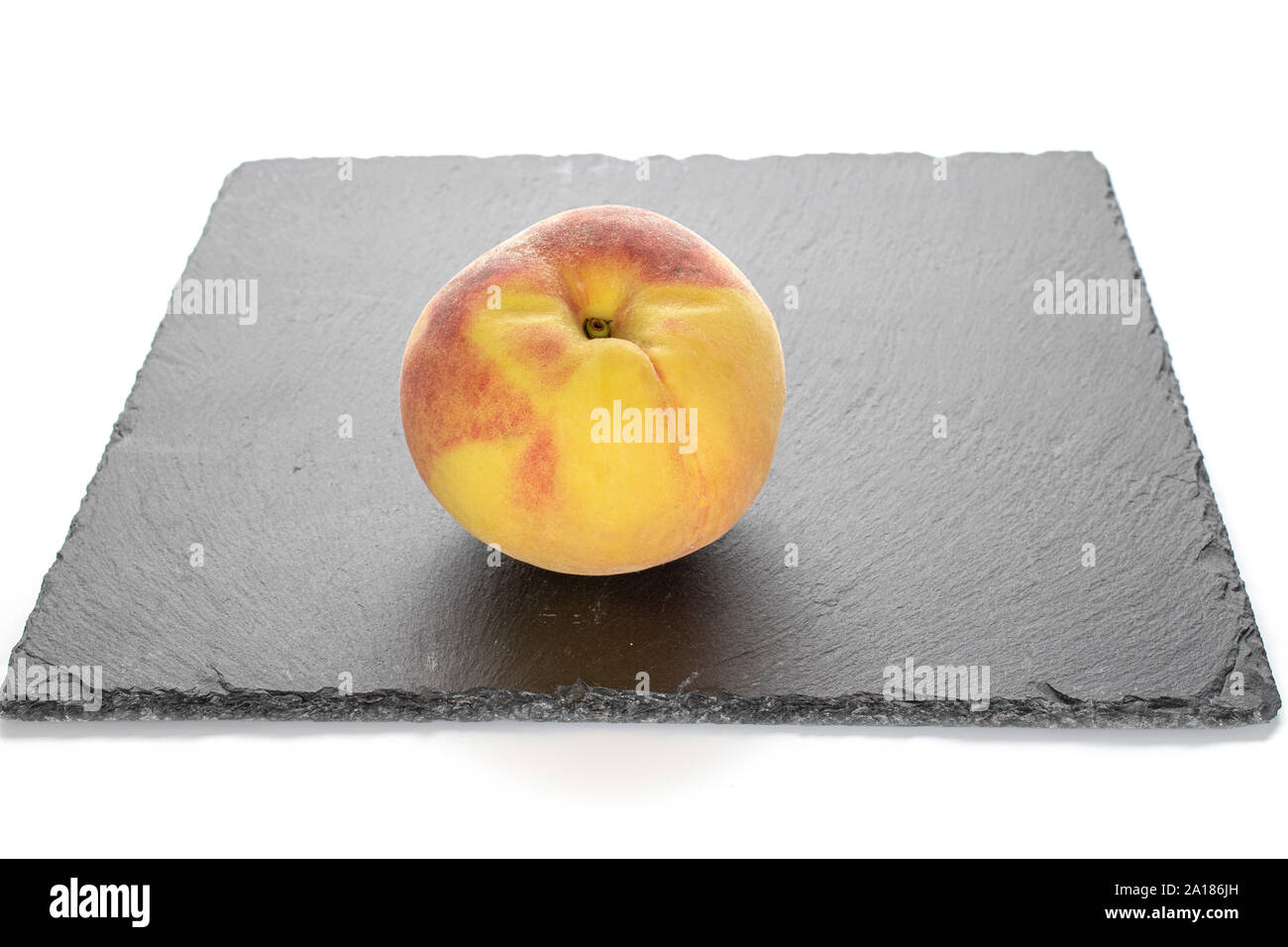One whole fresh fuzzy peach on grey stone isolated on white background ...