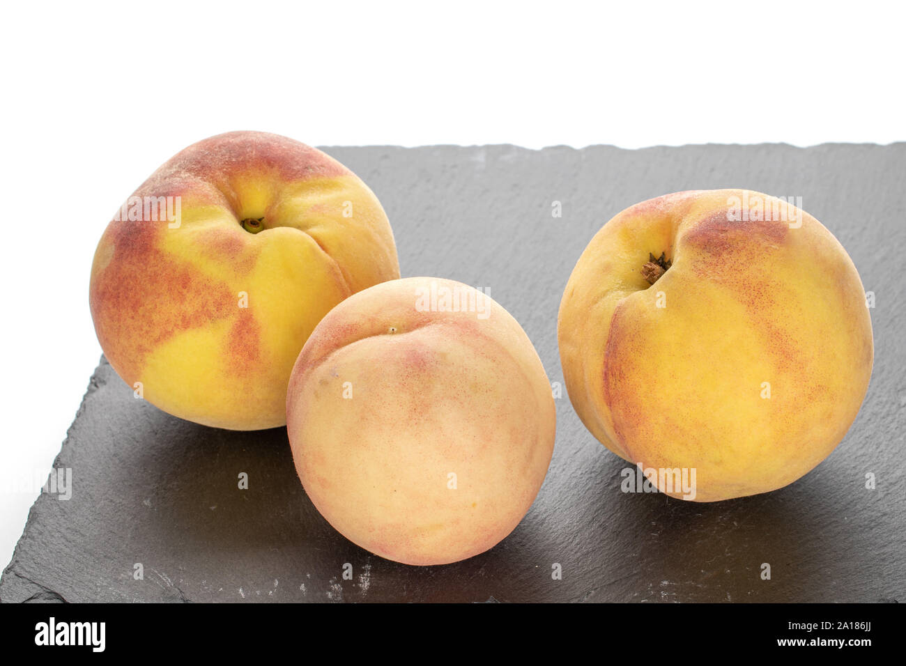 Group of three whole fresh fuzzy peach on grey stone isolated on white ...