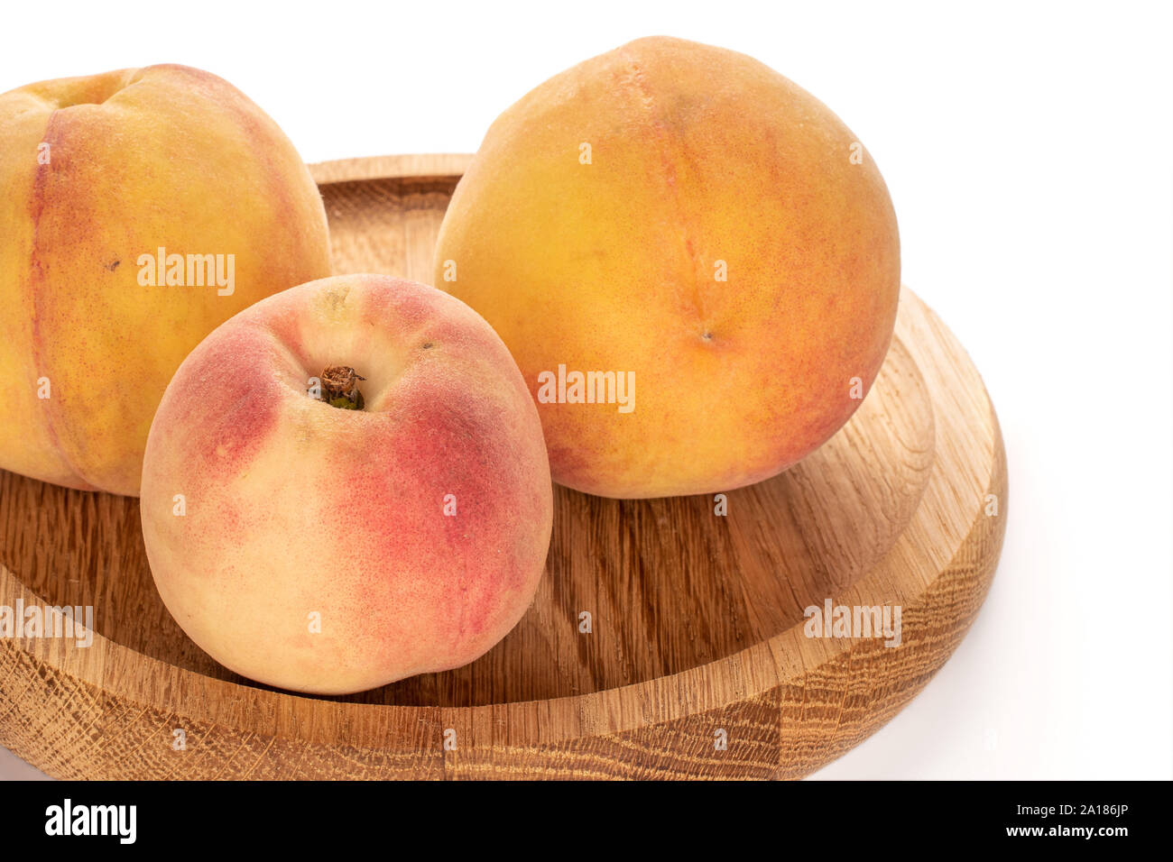 Group of three whole fresh fuzzy peach on bamboo plate isolated on ...